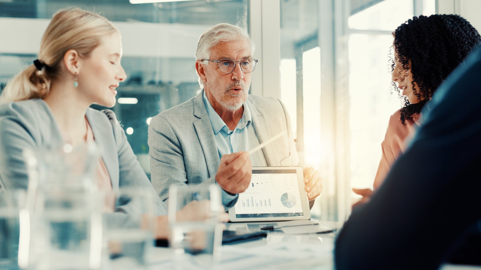 Presentation, businessman and tablet screen with charts in meeting, investment metrics or planning. Office, team or brainstorming with financial dashboard, data or performance analysis with kpi stats.